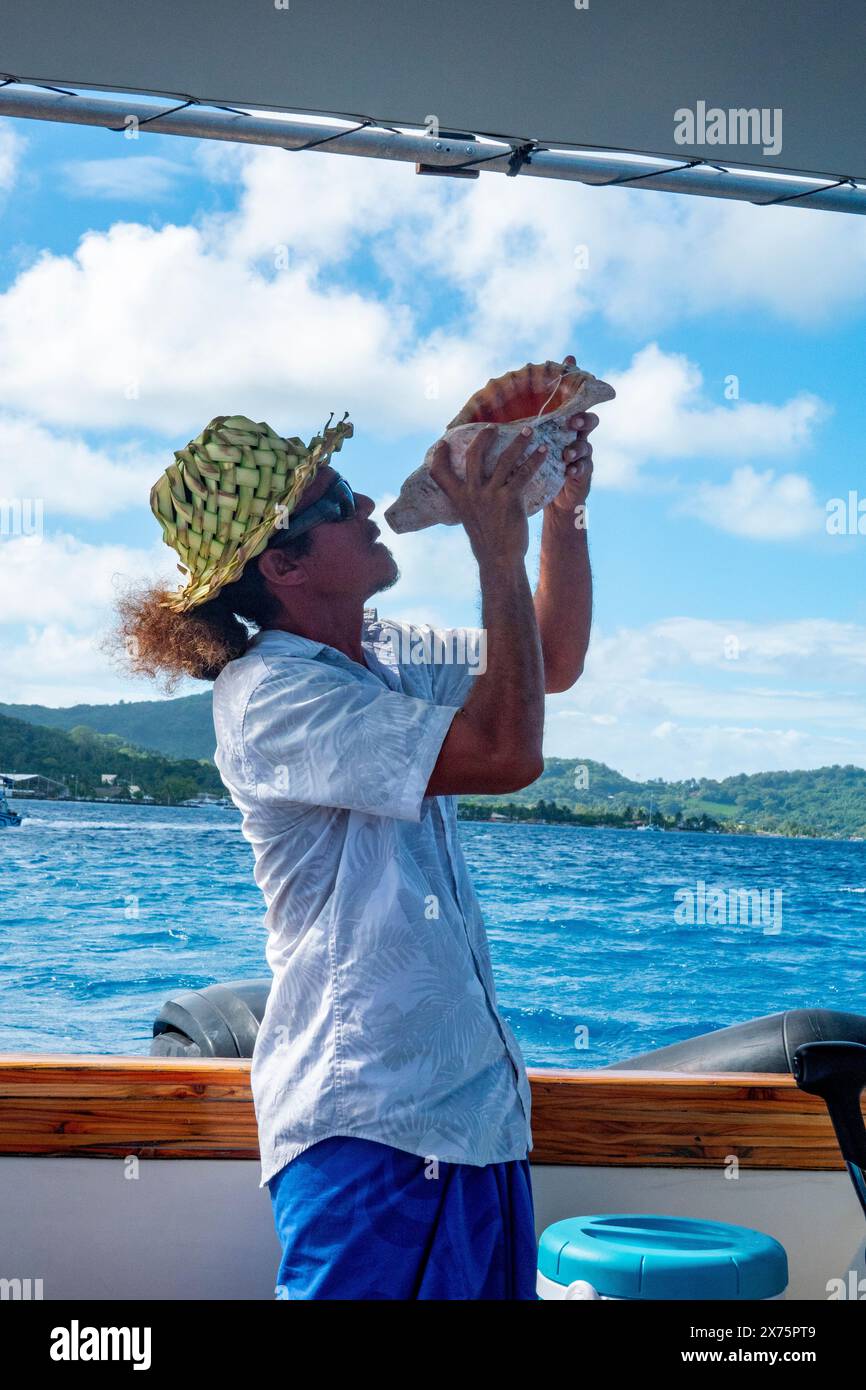 Polynesian man blowing in a seashell, Bora Bora, Society Islands ...