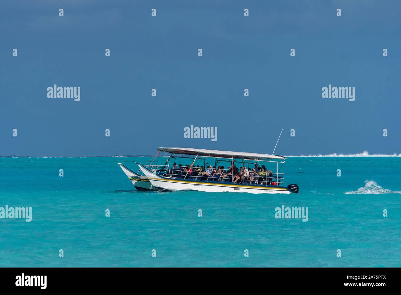 Tourists on a tour in a typical Polynesian Canoe over the lagoon and ...