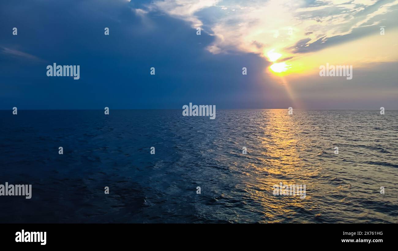 Blue ocean with sun rays coming through the clouds during sunrise or ...