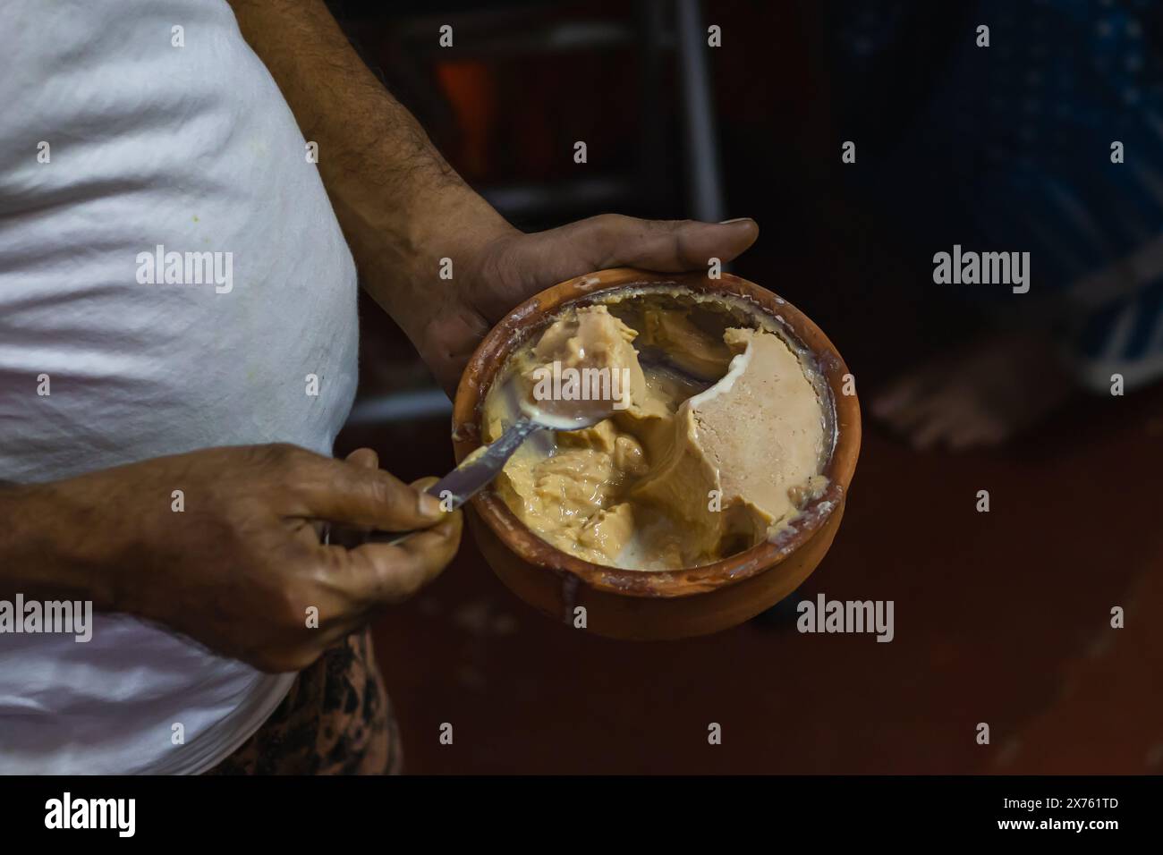 mishti doi or dahi or sweet yogurt being eaten from earthen bowl. This ...