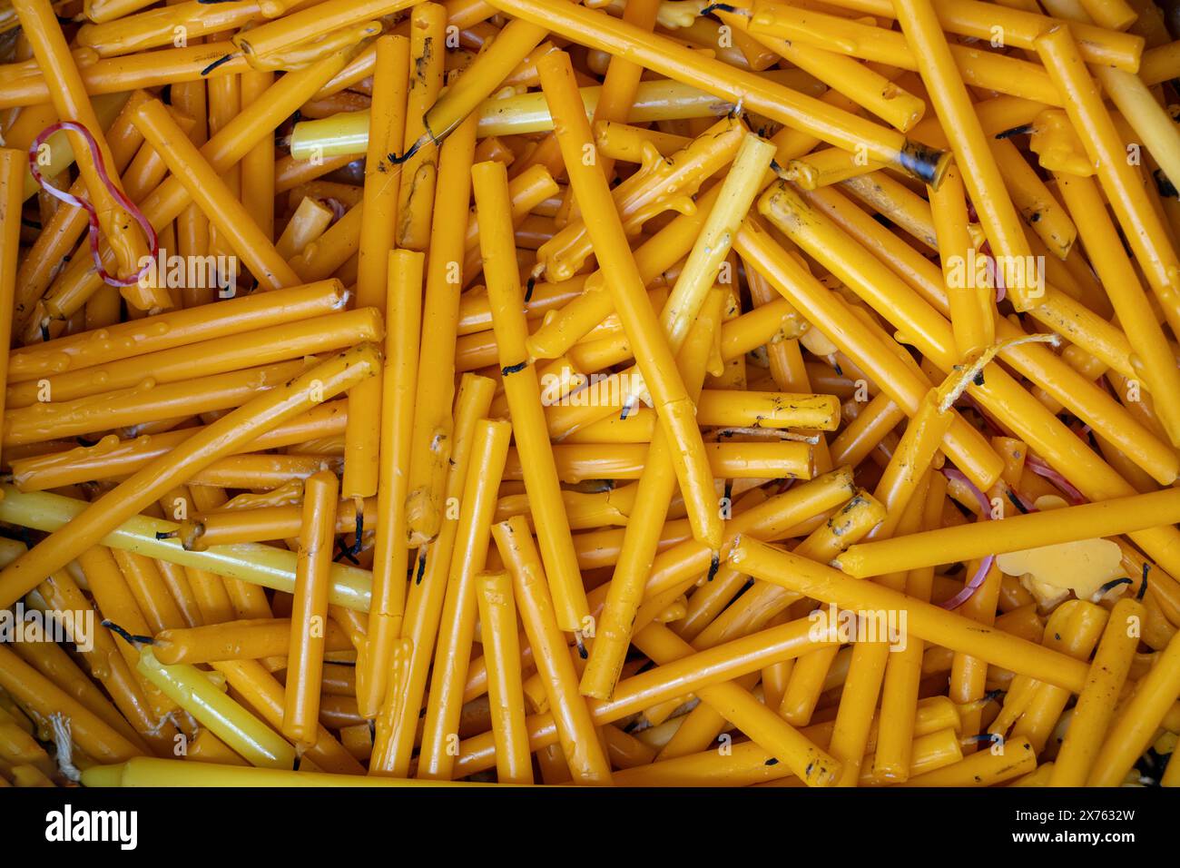 A pile of used candles in a container near an altar in a Buddhist ...