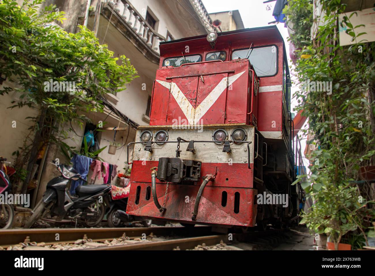 A locomotive with wagons passes through a narrow street in the city ...