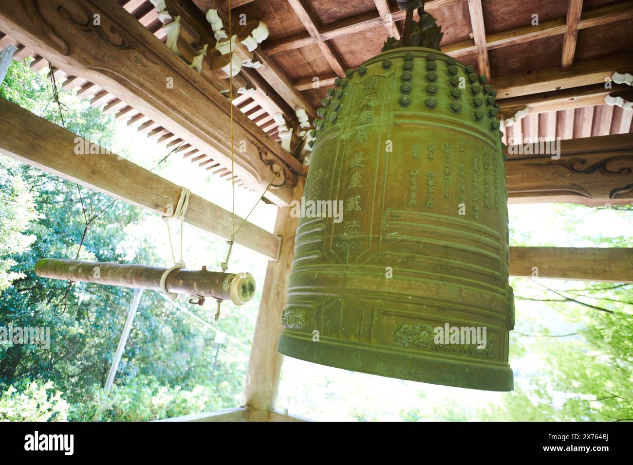 Large copper bell hanging under a wooden canopy at a Japanese graveyard ...
