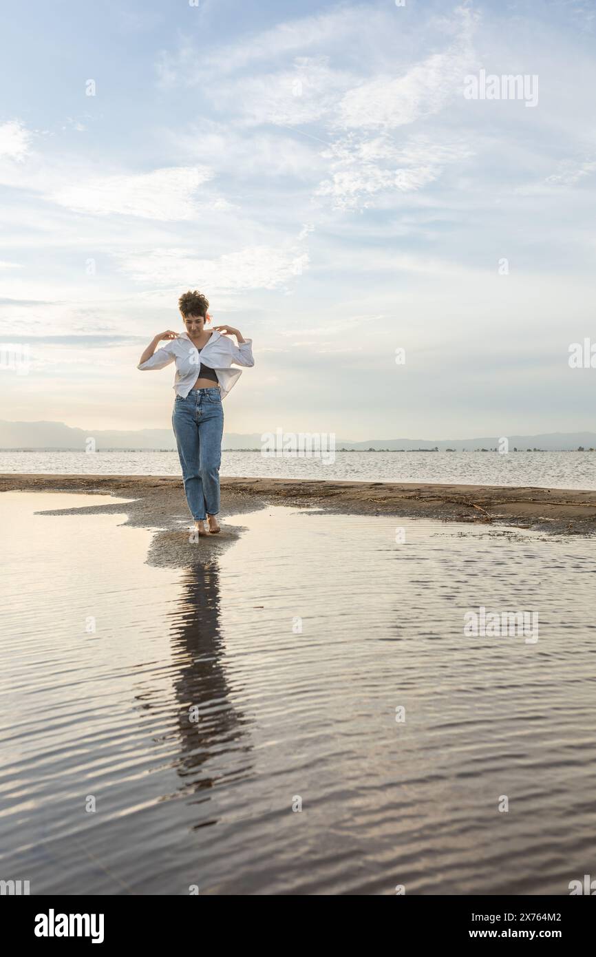 woman on the beach dancing at sunset in backlight with the sun behind ...
