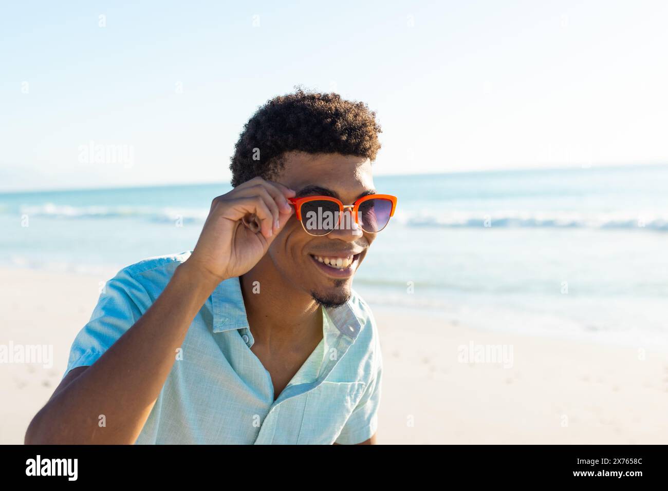 At beach, biracial young man wearing sunglasses, smiling Stock Photo ...
