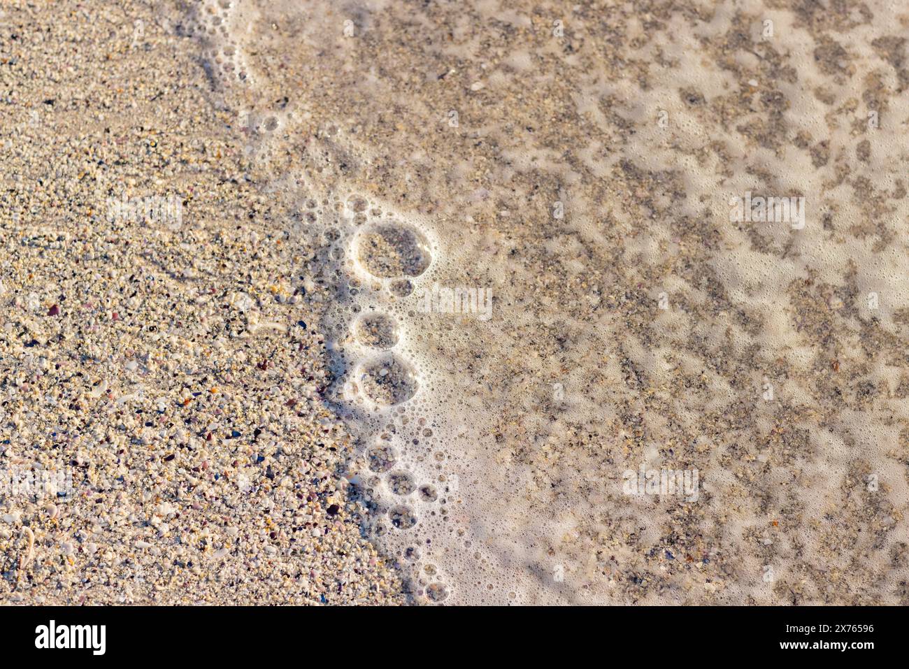 At beach, foam bubbles forming on sandy shore as wave receding Stock ...
