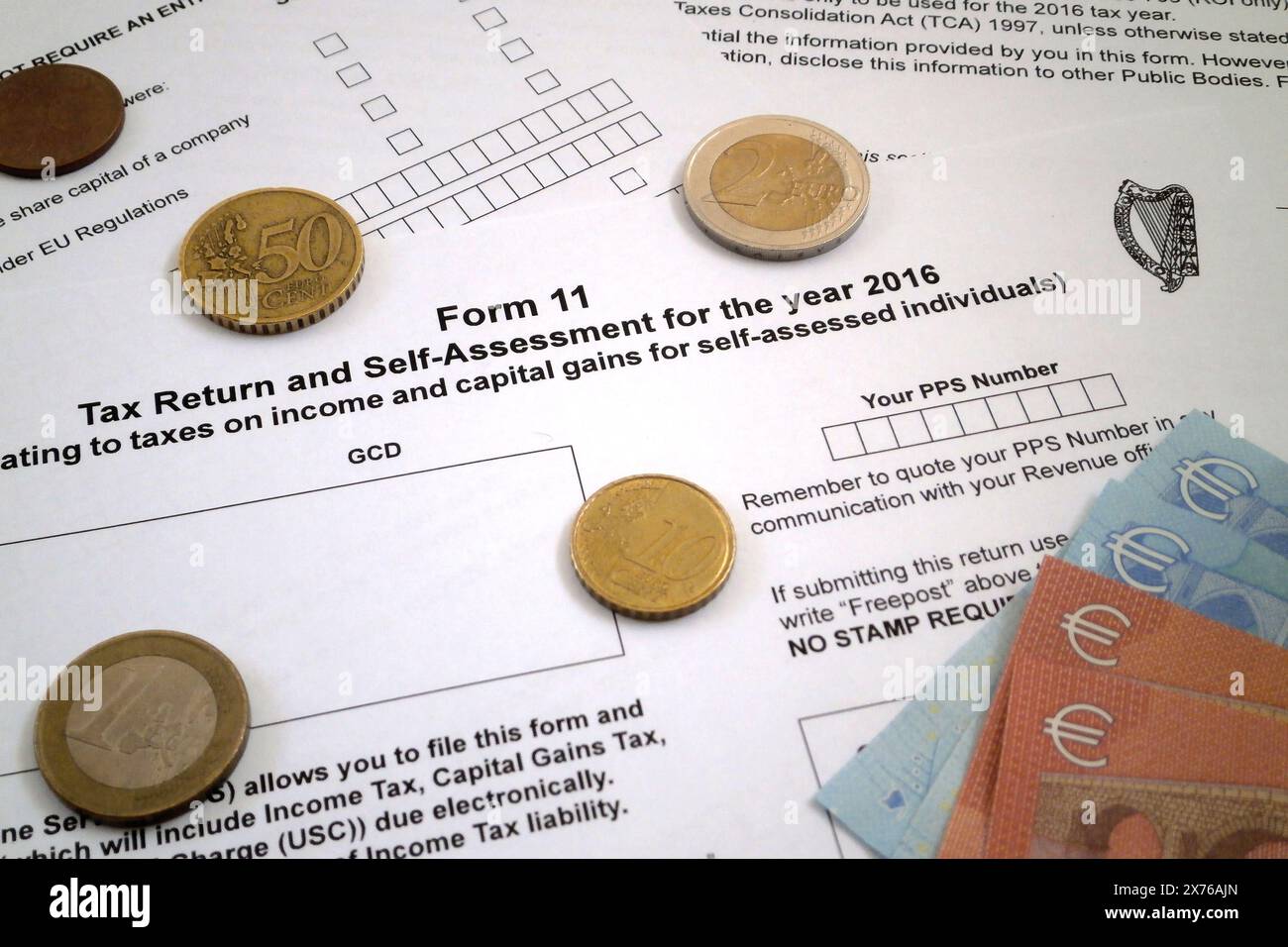 Some euro coins and banknotes on the top of an Irish tax return form ...
