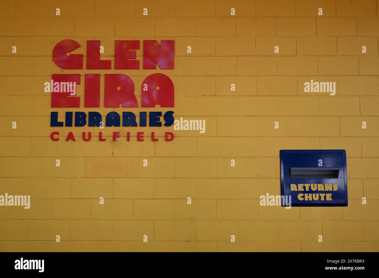 Yellow wall featuring signage and a return chute outside Caulfield ...