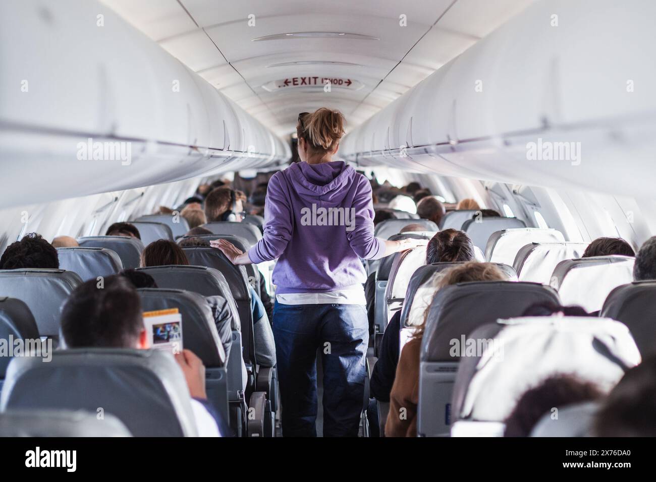 Interior of airplane with passengers on seats and female traveler ...