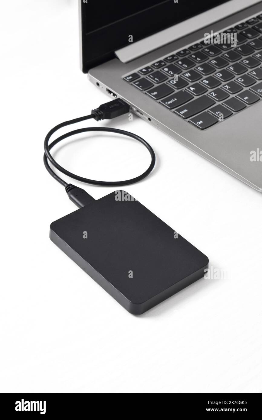 External backup hard disk drive connected to laptop on white background ...