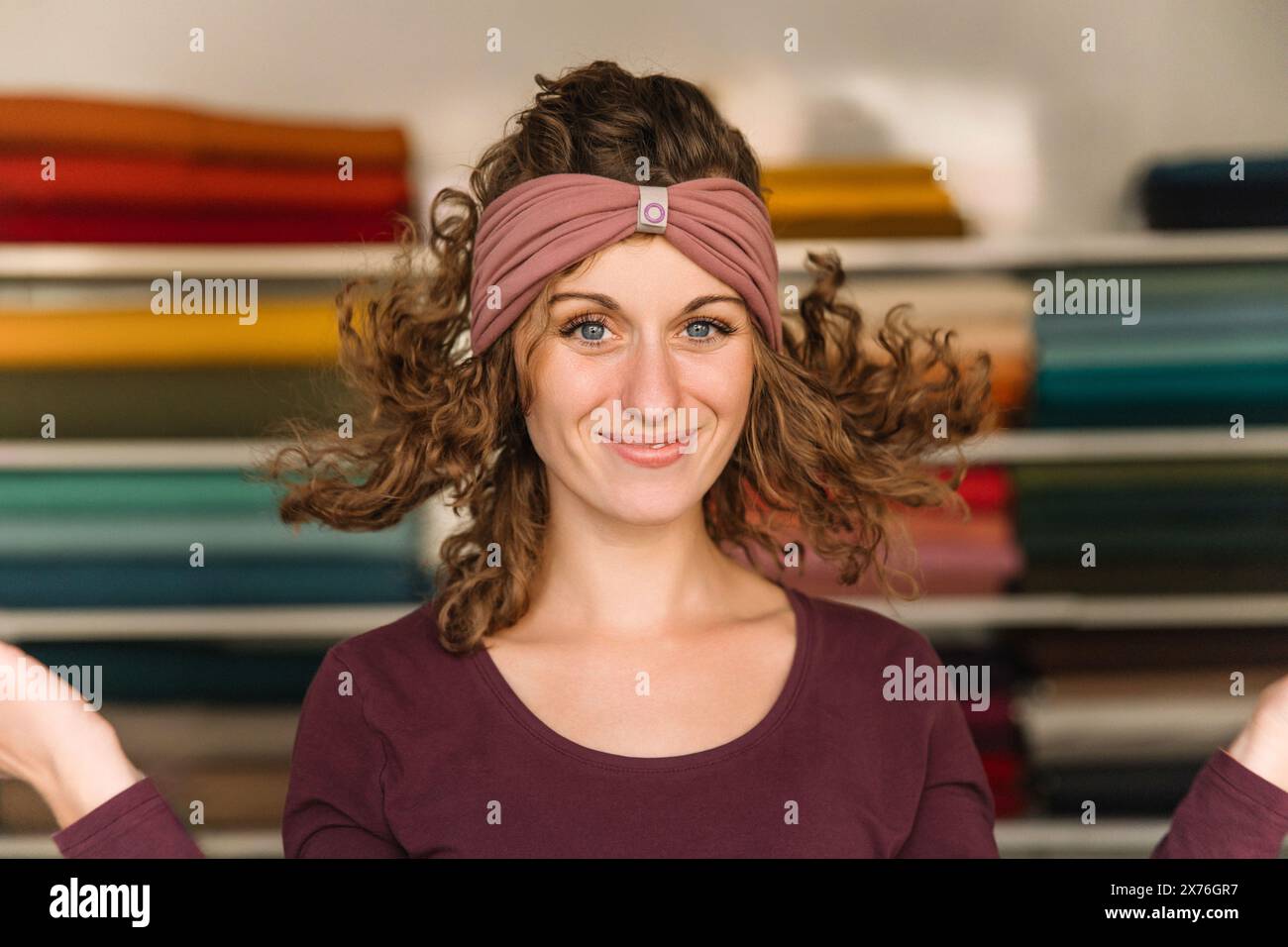 A joyful fashion designer with expressive eyes and curly hair poses ...