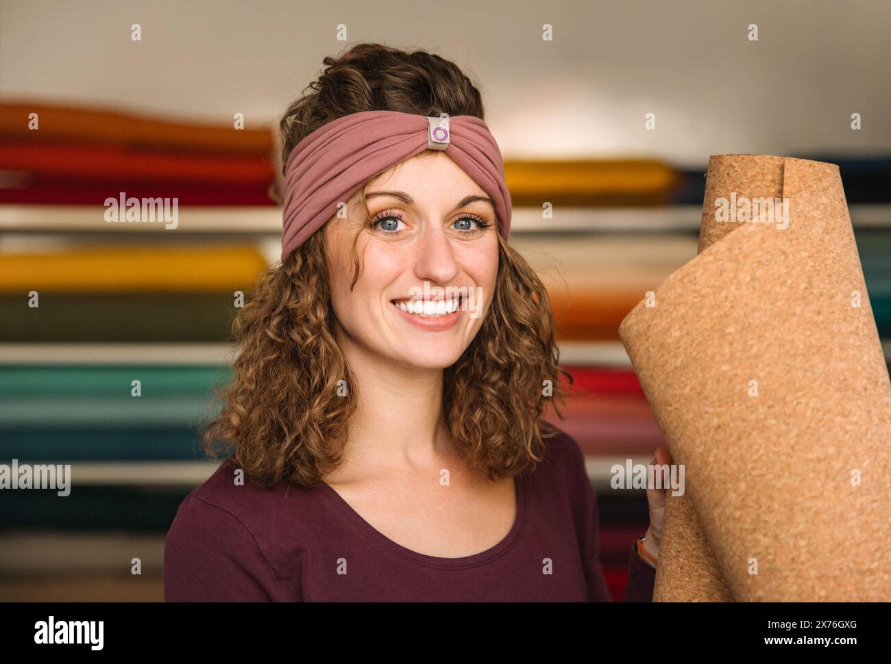 Cheerful designer holds a sheet of cork, her joyful expression ...