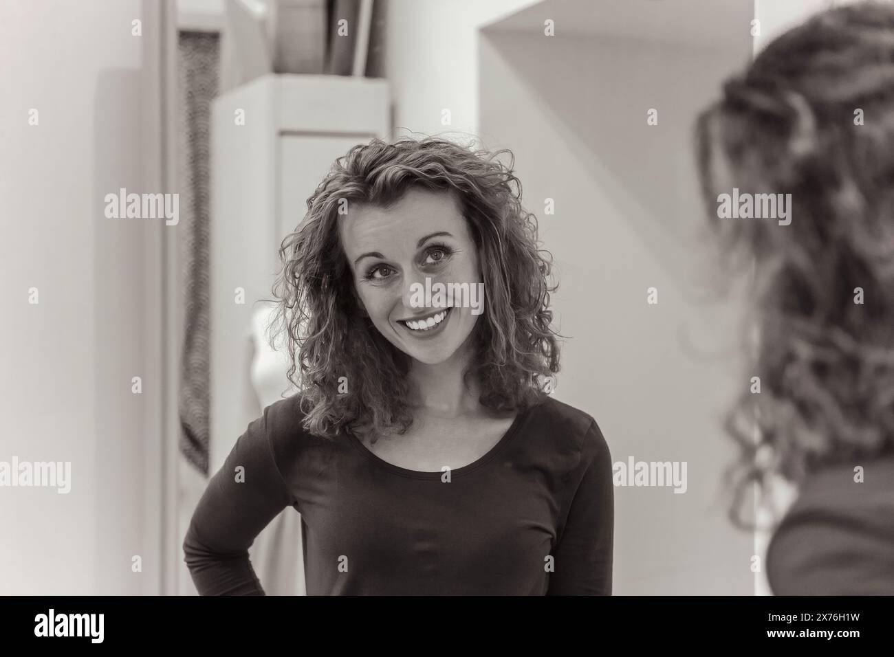 Smiling Woman with Curly Hair Viewing Her Reflection in a Dressing Room ...