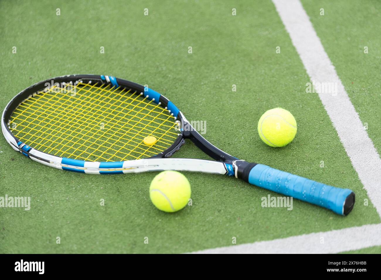 Tennis ball and racket on the ground of sunny outdoor grass tennis ...