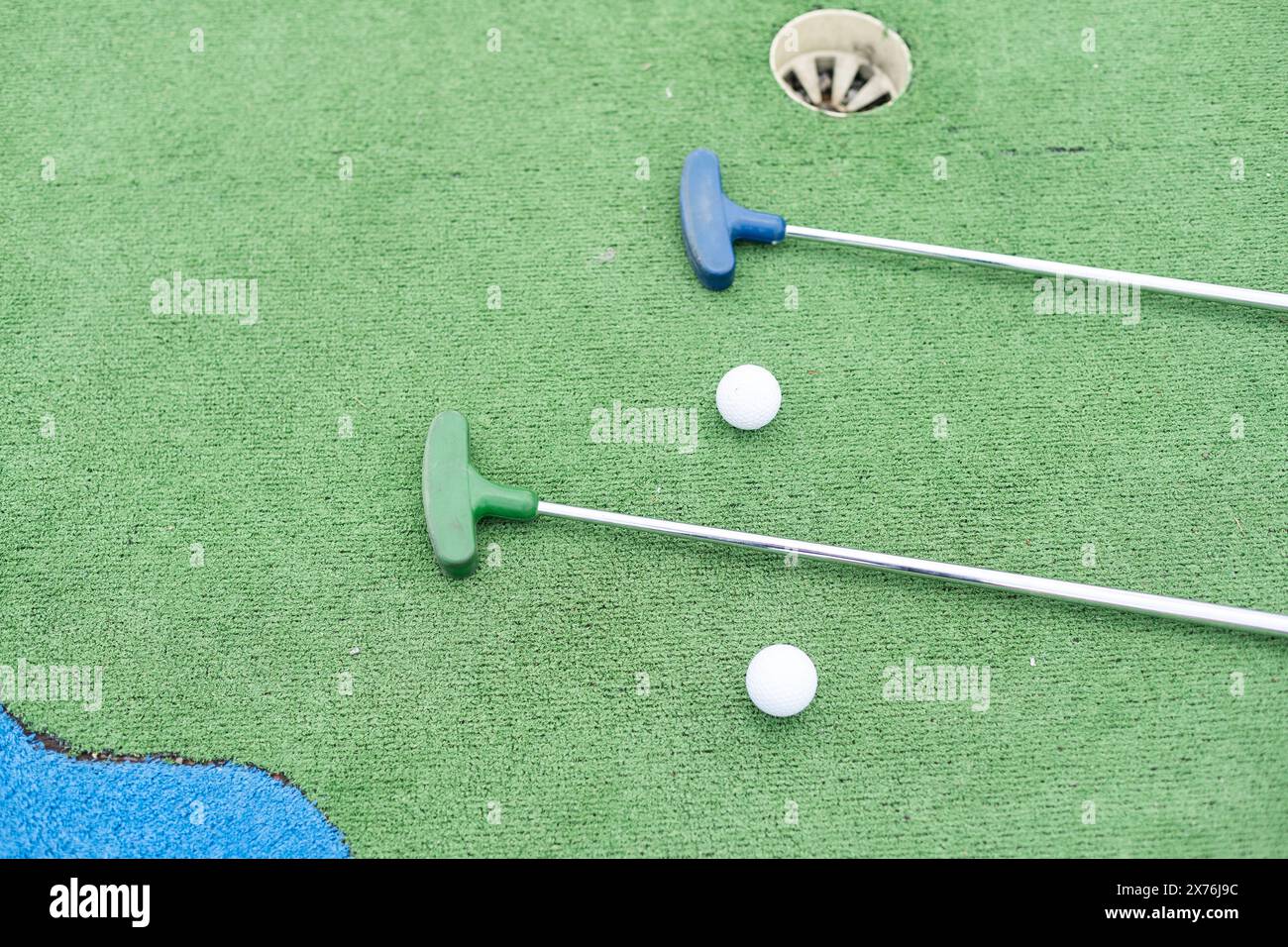 Mini-golf clubs and balls of different colors laid on artificial grass ...