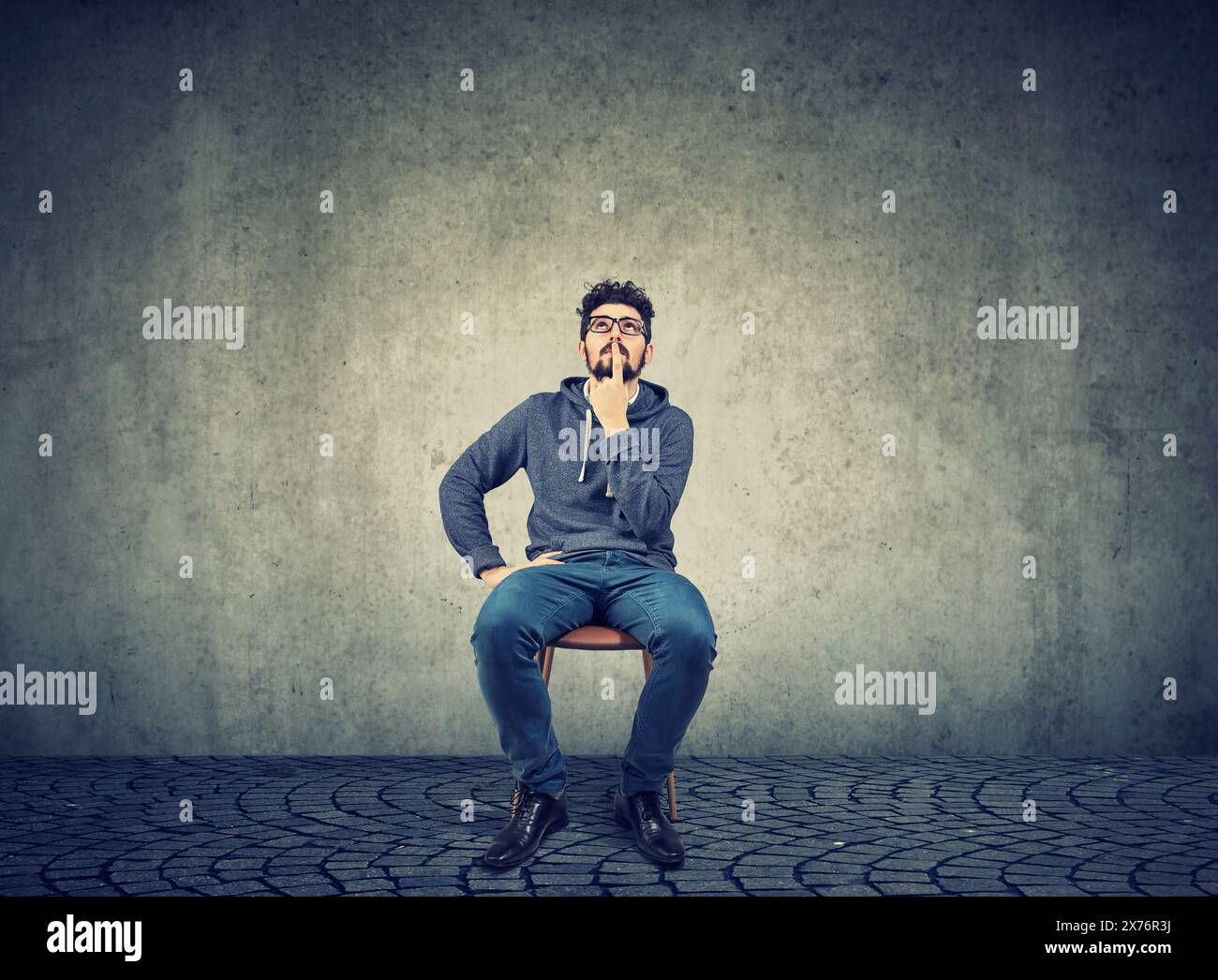 handsome man sitting on a chair thinking looking up Stock Photo - Alamy
