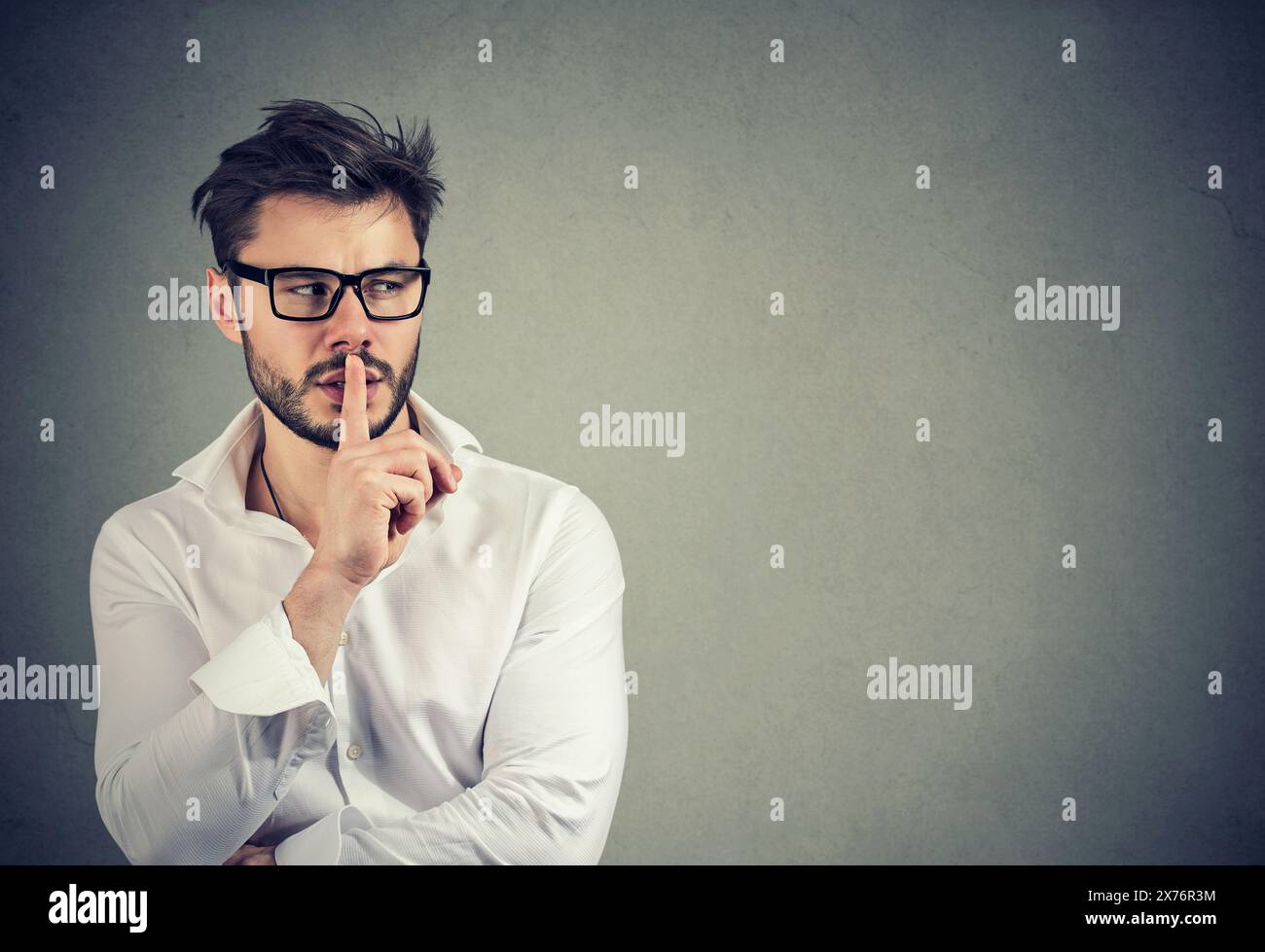 young man giving a shh quiet finger to lips gesture Stock Photo - Alamy