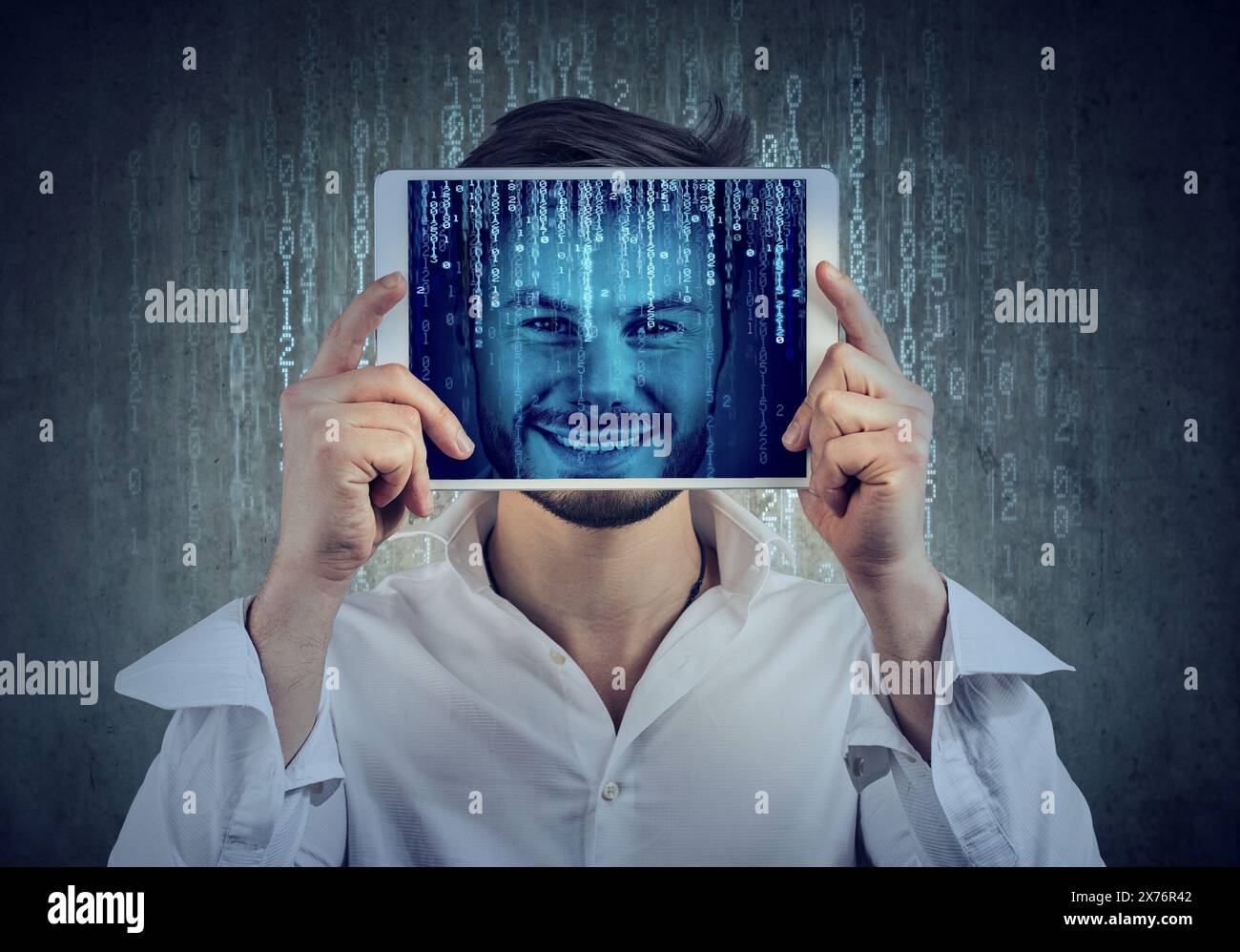 Happy young man holding tablet with his face displayed on a screen with binary code Stock Photo ...