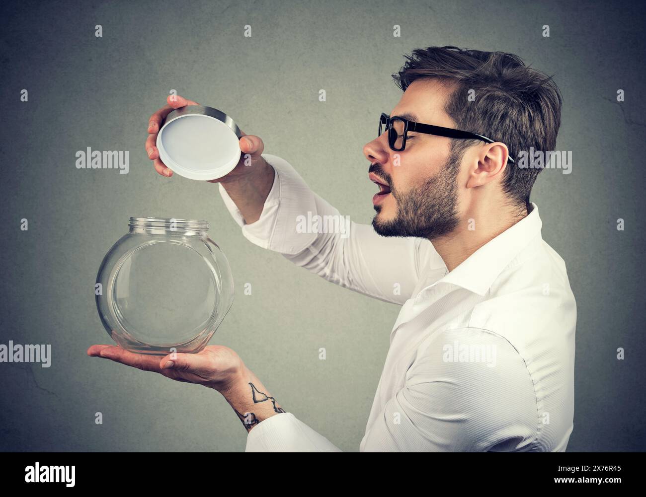 Curious young man opens an empty glass jar Stock Photo - Alamy