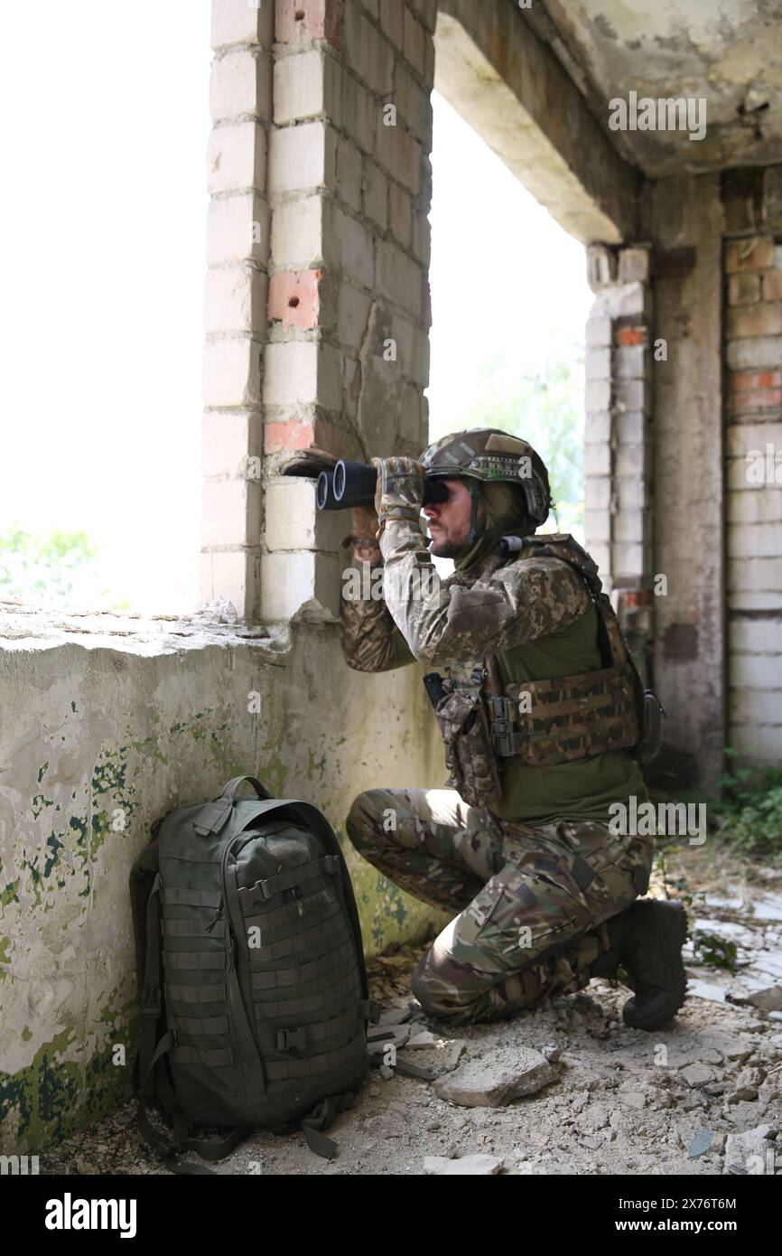 Military mission. Soldier in uniform with binoculars inside abandoned ...