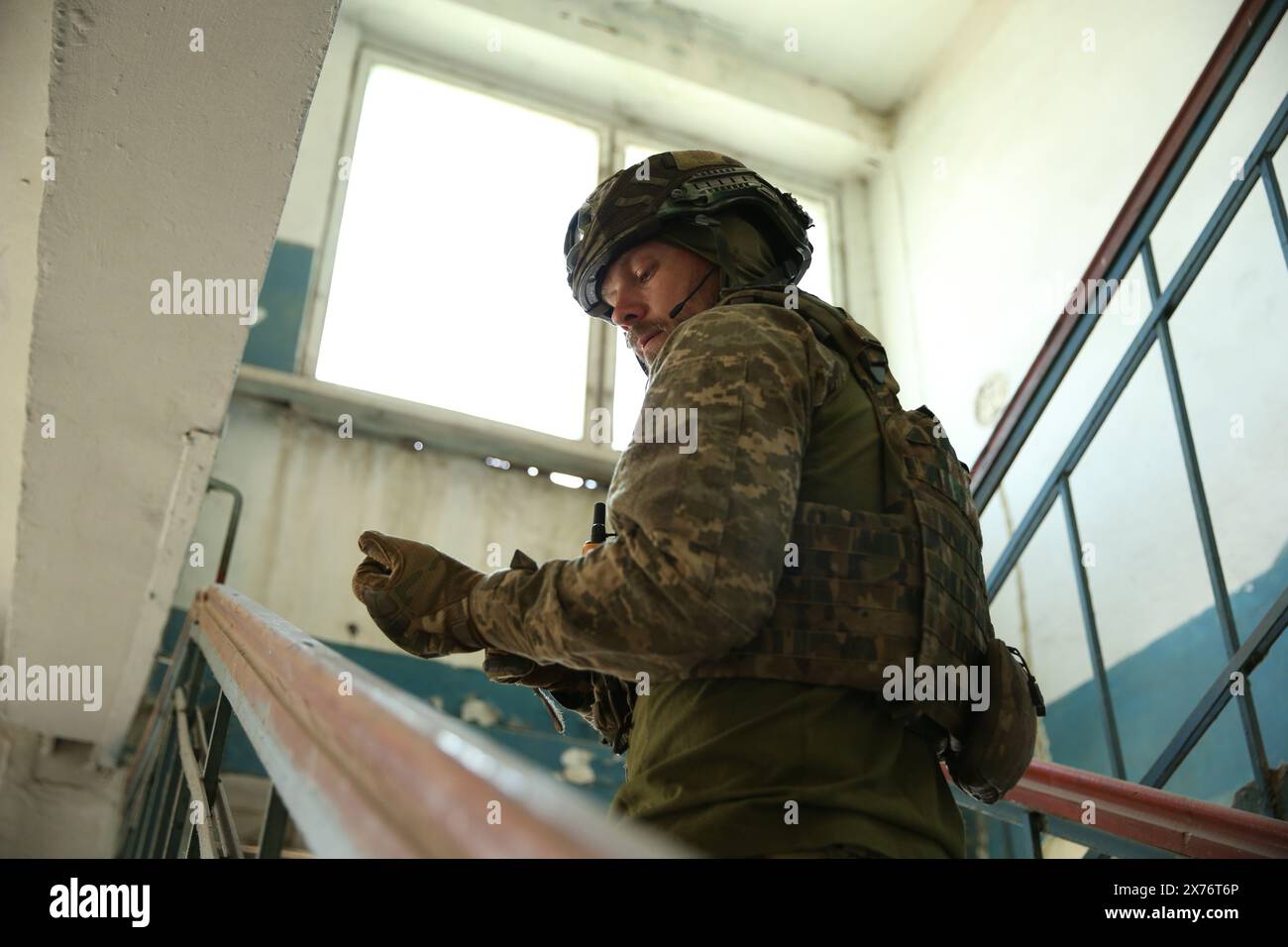 Military mission. Soldier in uniform on stairs inside abandoned ...