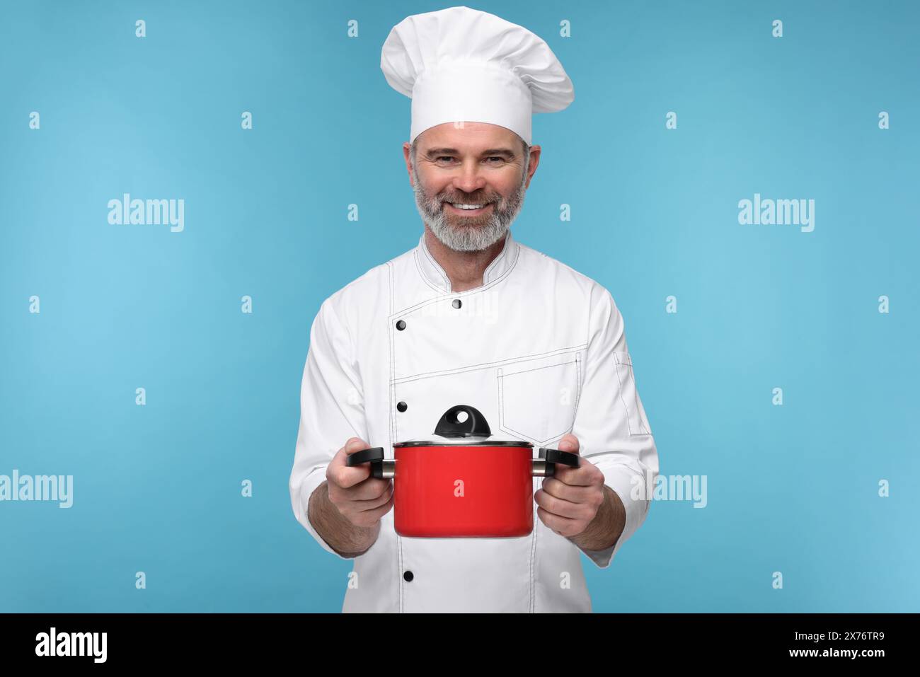 Happy chef in uniform with cooking pot on light blue background Stock ...