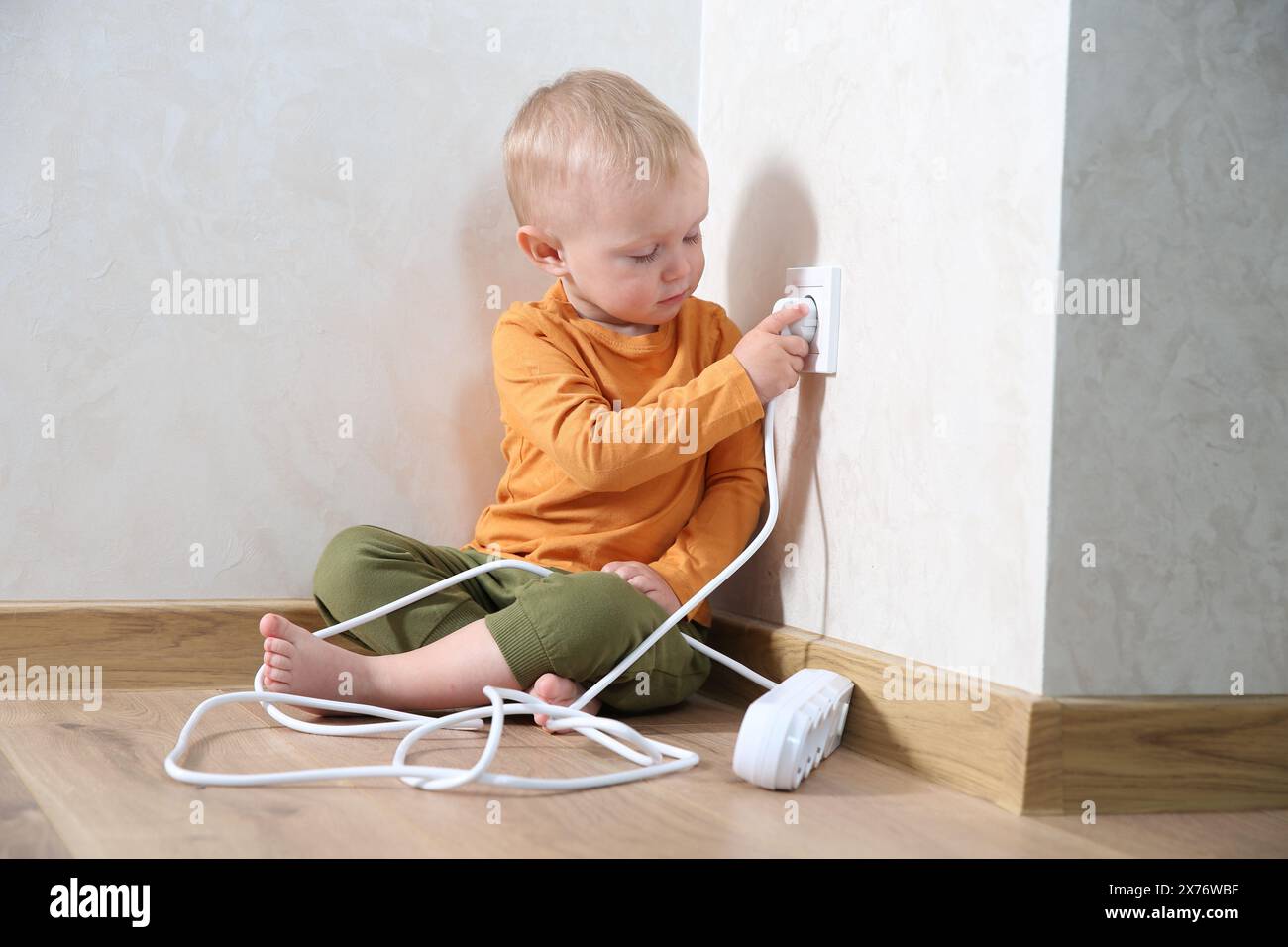 Little child playing with electrical socket and power strip plug at ...