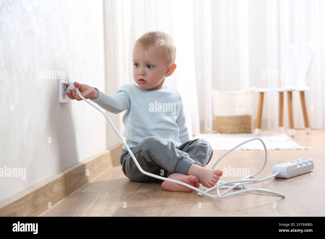 Little child playing with electrical socket and power strip plug at ...