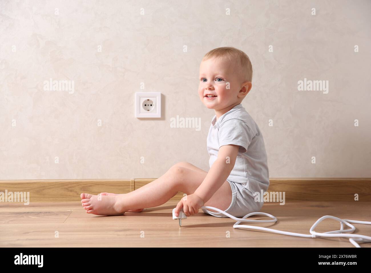 Little child playing with plug near electrical socket indoors ...