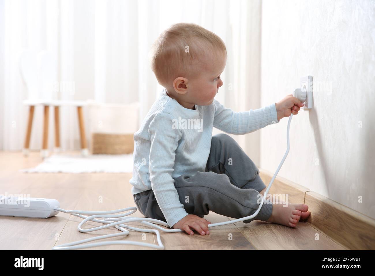 Little child playing with electrical socket and power strip plug at ...