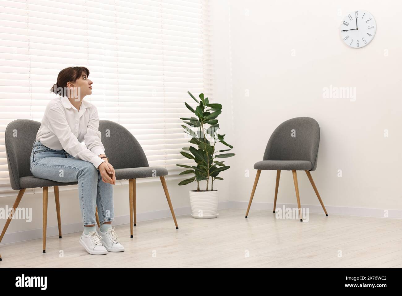 Woman sitting on chair and waiting for appointment indoors Stock Photo ...