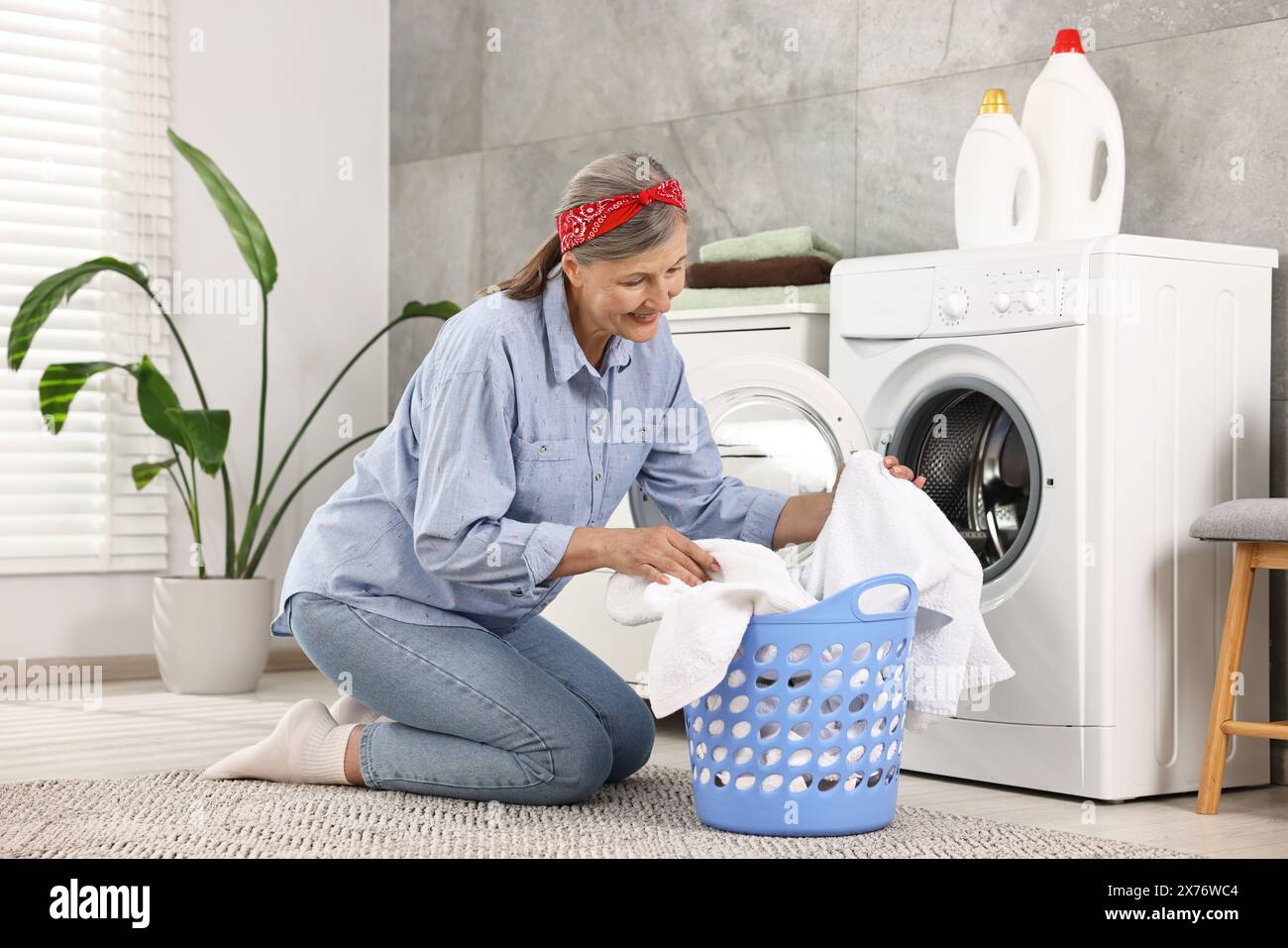 Happy housewife with laundry basket near washing machine at home Stock ...