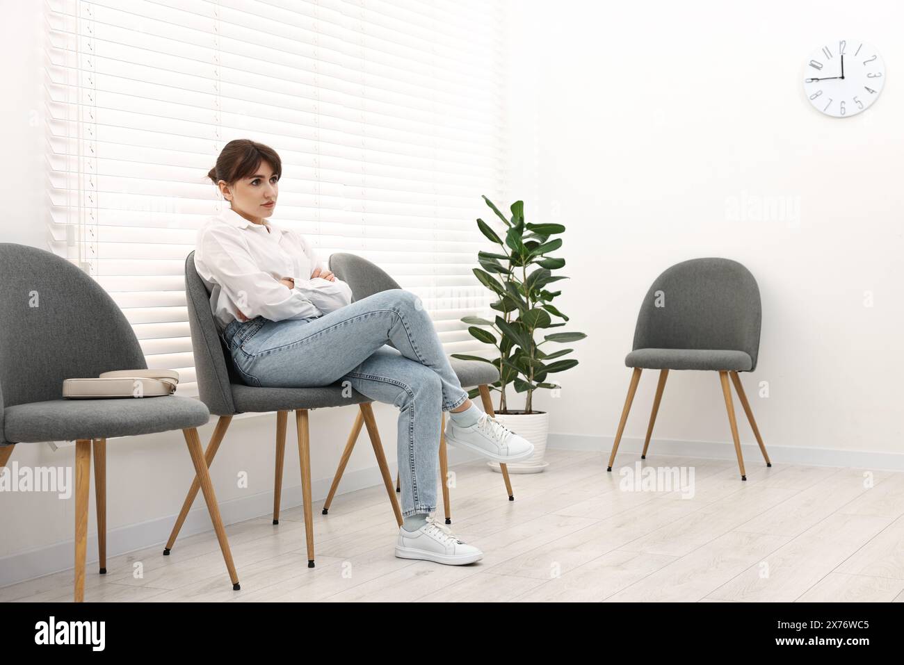 Woman sitting on chair and waiting for appointment indoors Stock Photo ...