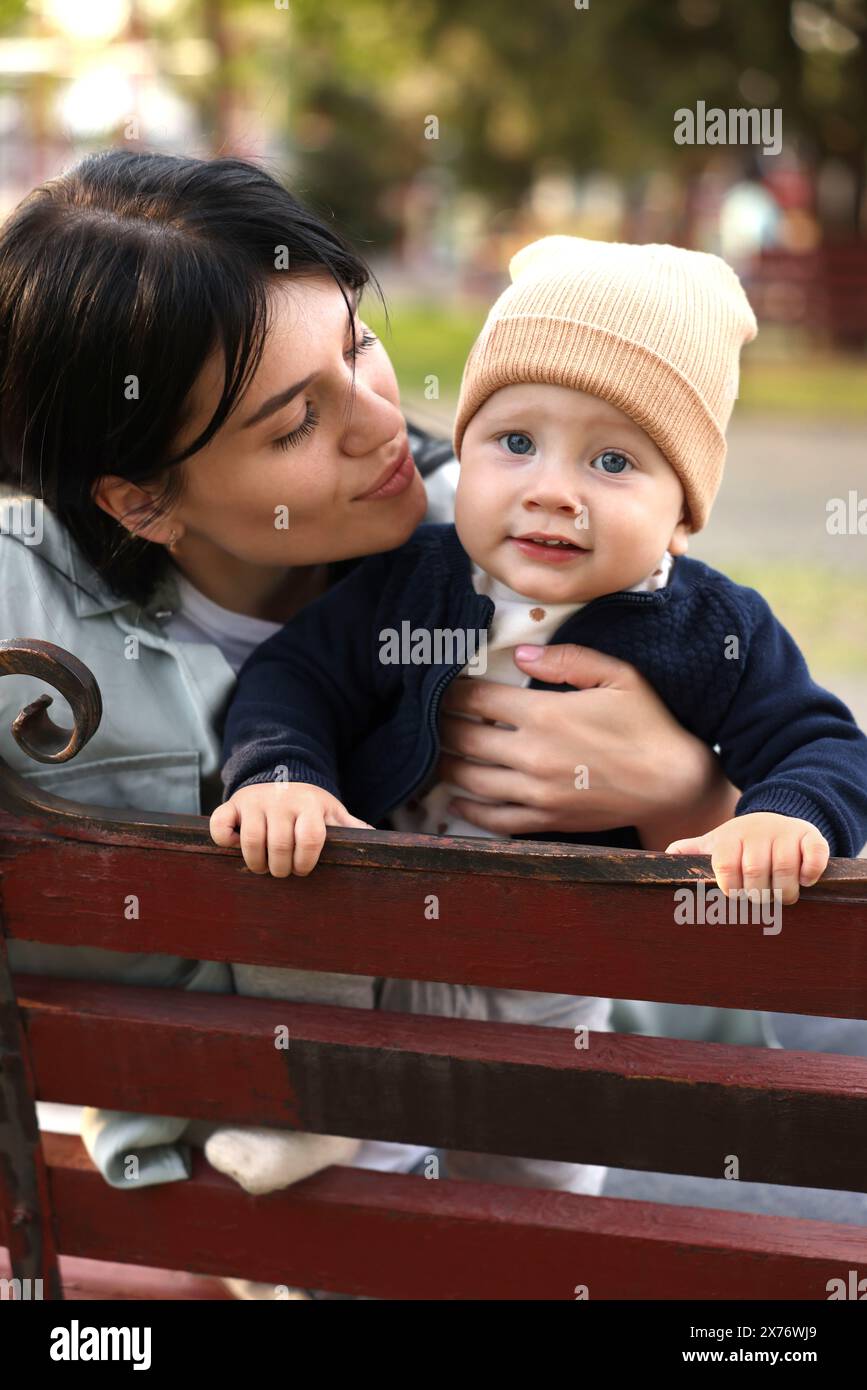 Mother kissing her baby on bench in park Stock Photo - Alamy