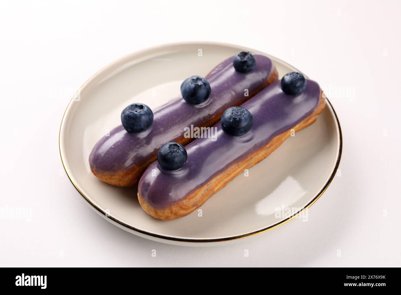 Delicious eclairs decorated with blueberries on white background Stock ...