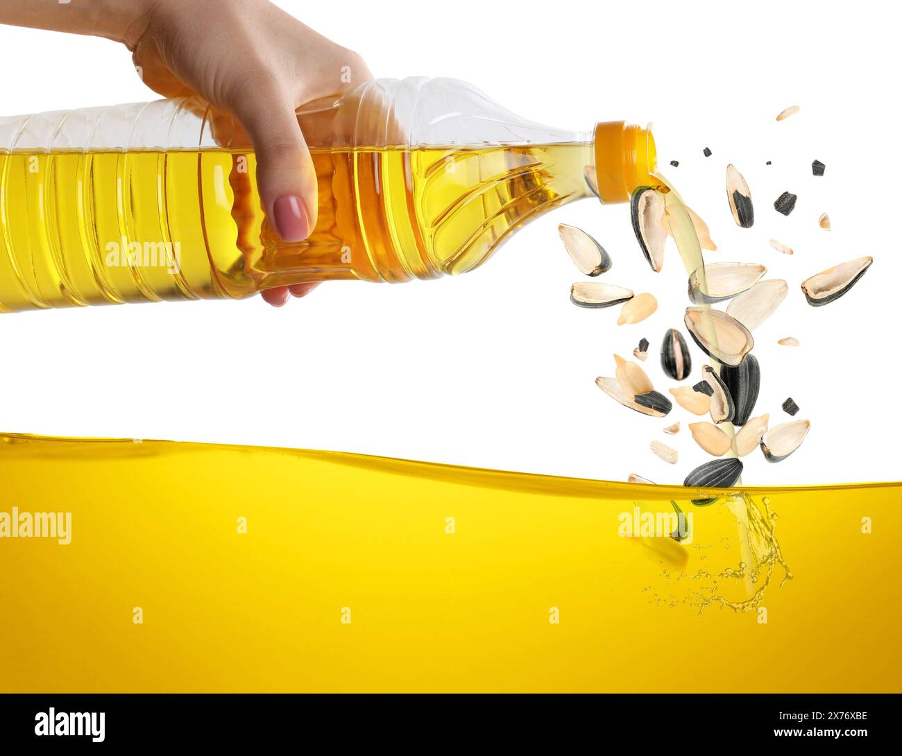 Woman pouring sunflower oil on white background. Seeds falling into ...