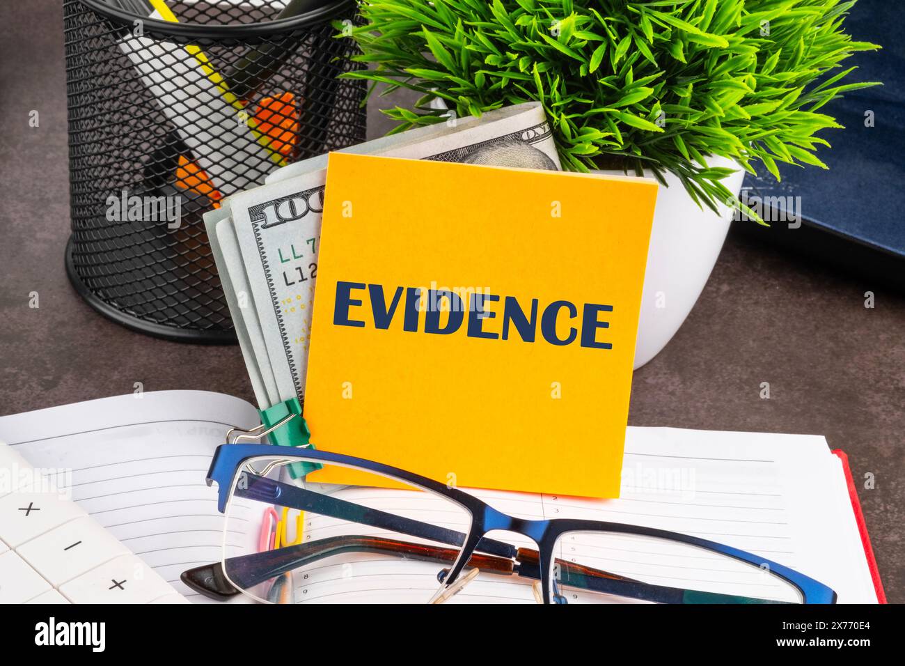 Word EVIDENCE composed on a yellow sticker with dollars, on the desktop ...