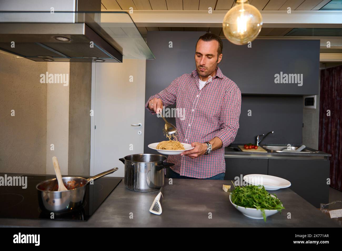 Authentic portrait of a handsome guy at home kitchen, plating up ...