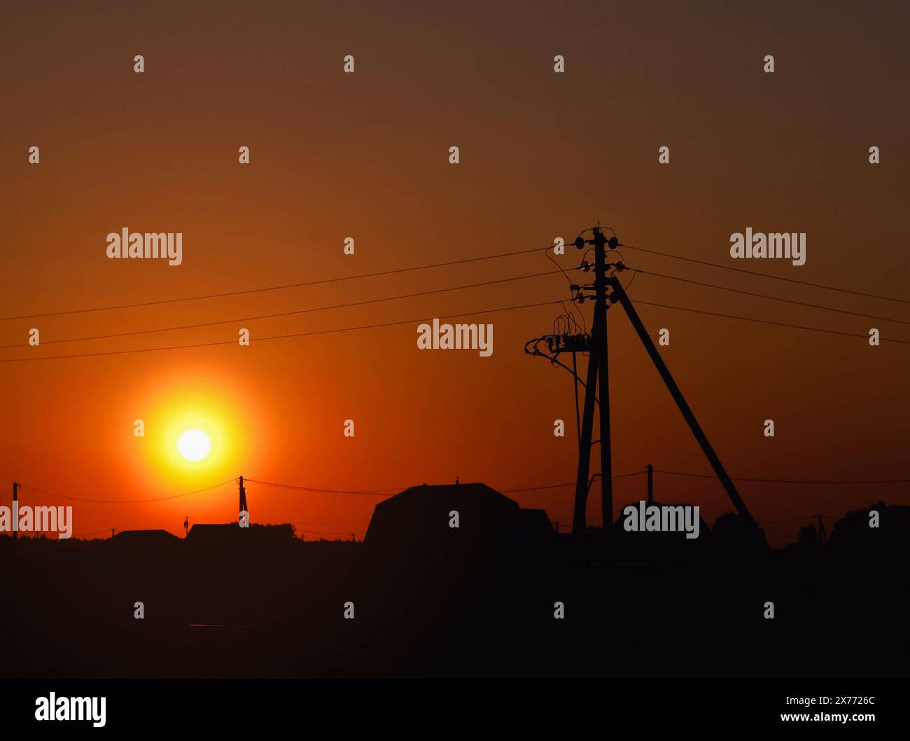 Power line pole silhouette and building silhouettes against bright sun ...
