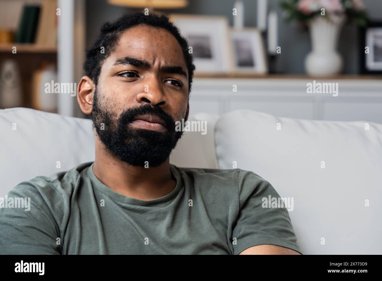 Close up portrait of young African American man sitting at home with ...