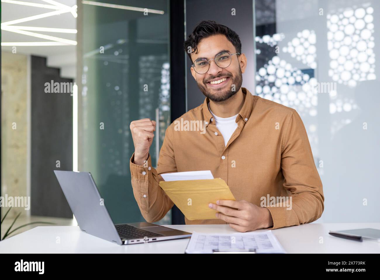 Happy businessman celebrates success, reading letter in a modern office ...