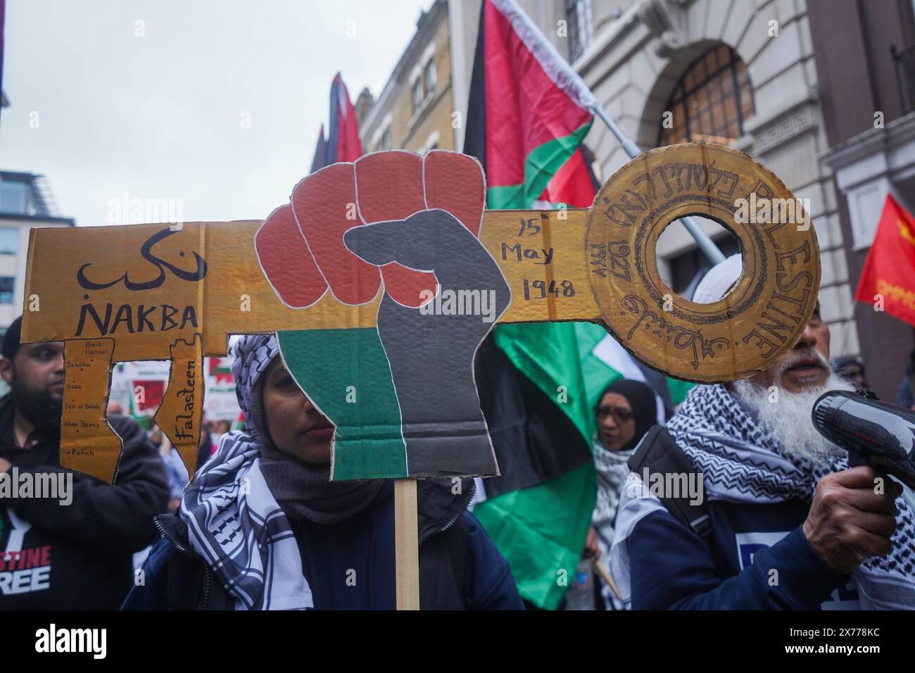 London, UK. 18 May, 2024. Protesters carry a key symbol of a home lost ...