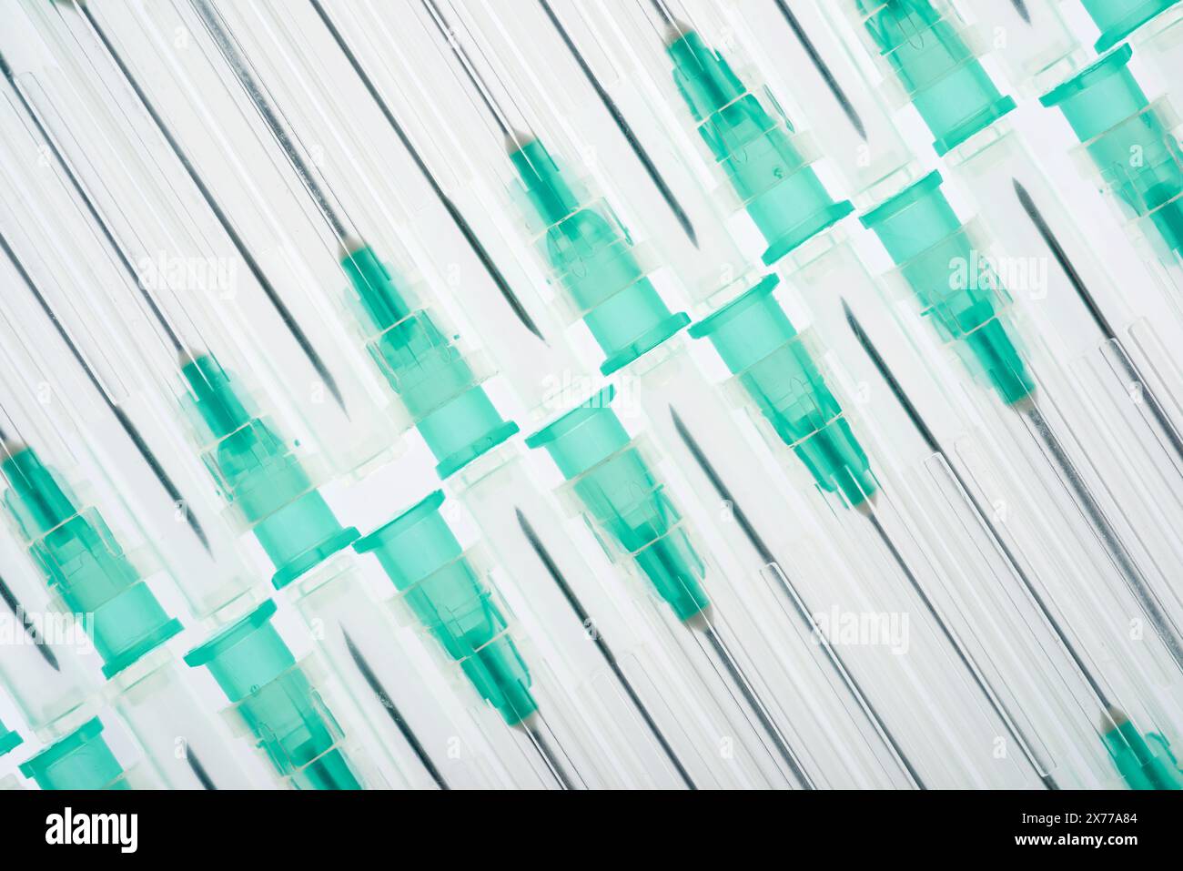 Close up of a group of hypodermic syringe needles on a white surface ...