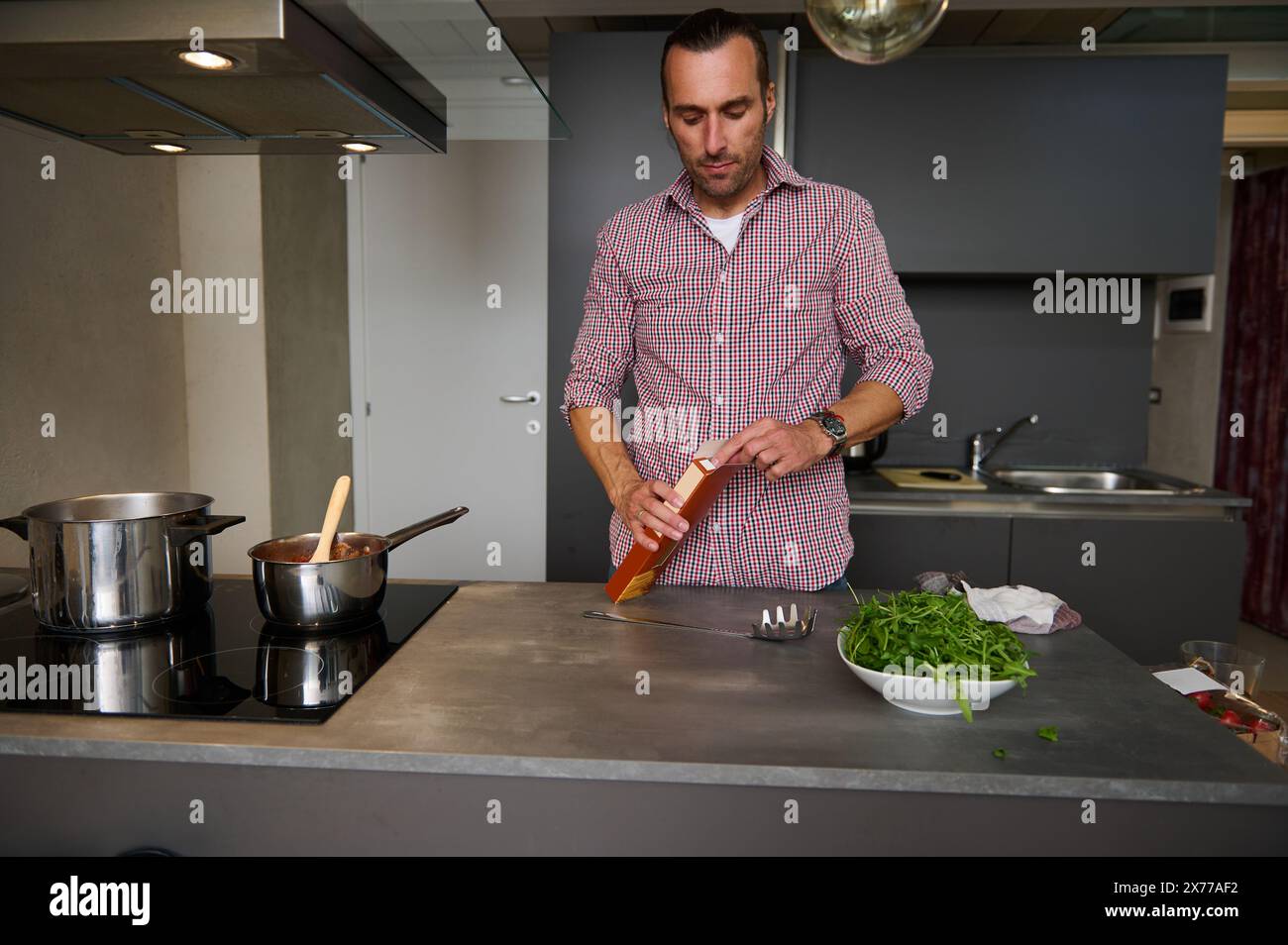 Young man chef opening a cardboard pack with integral Italian pasta ...