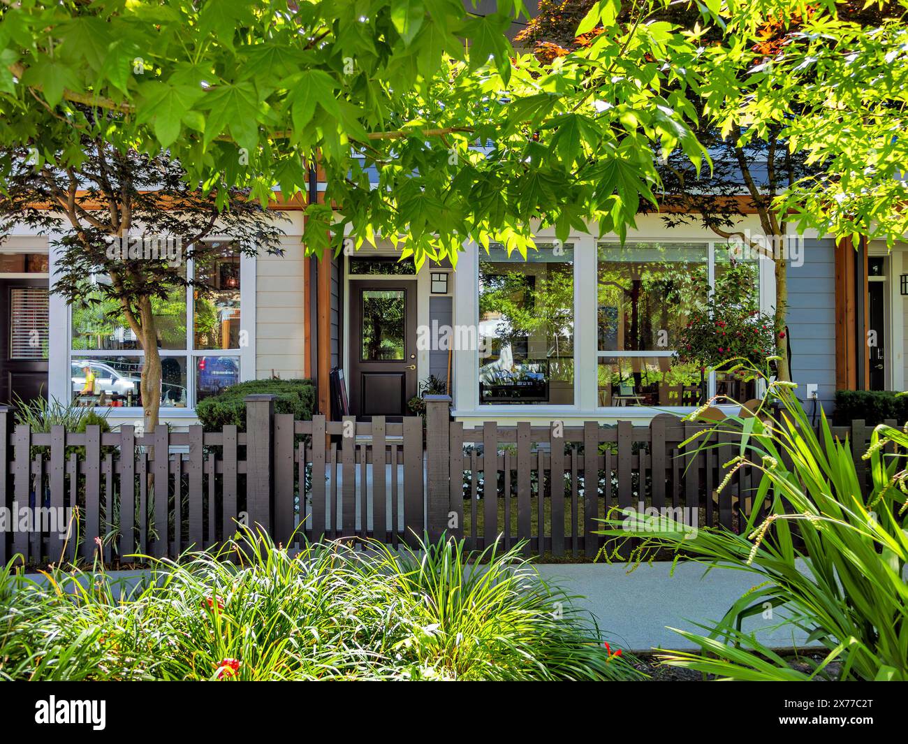 Front side of residential units with small yards and concrete walkway ...