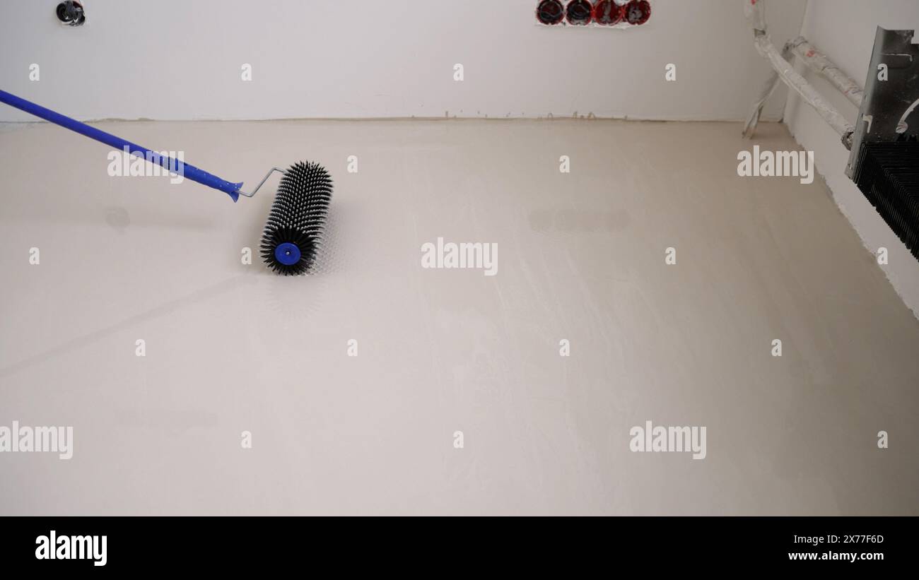 The process of leveling the self-leveling floor. Worker applying epoxy ...