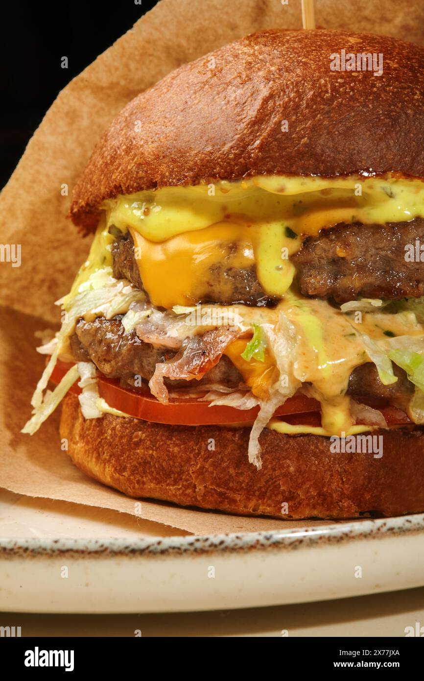 Burger with two beef patties in paper wrapping Stock Photo - Alamy