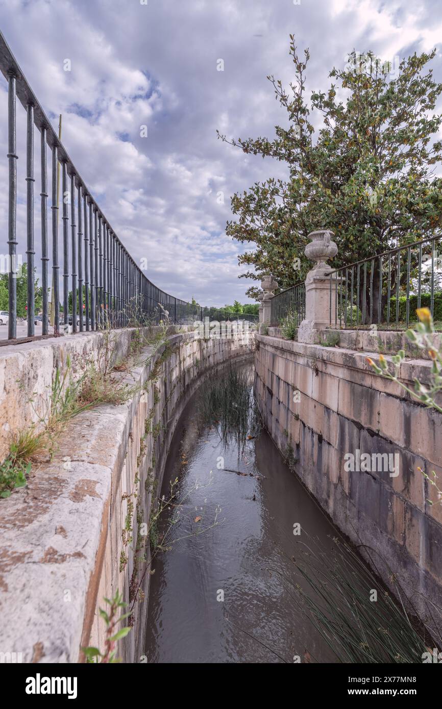 a water channel through stone walls and metal railings on a day with ...