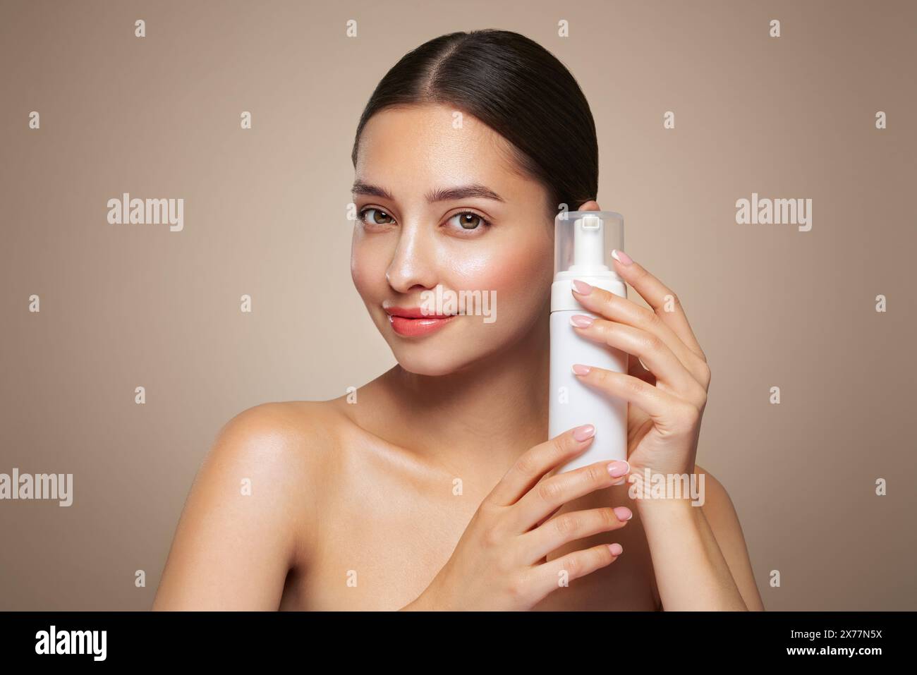 A young woman shows off a bottle with a foam dispenser for washing ...