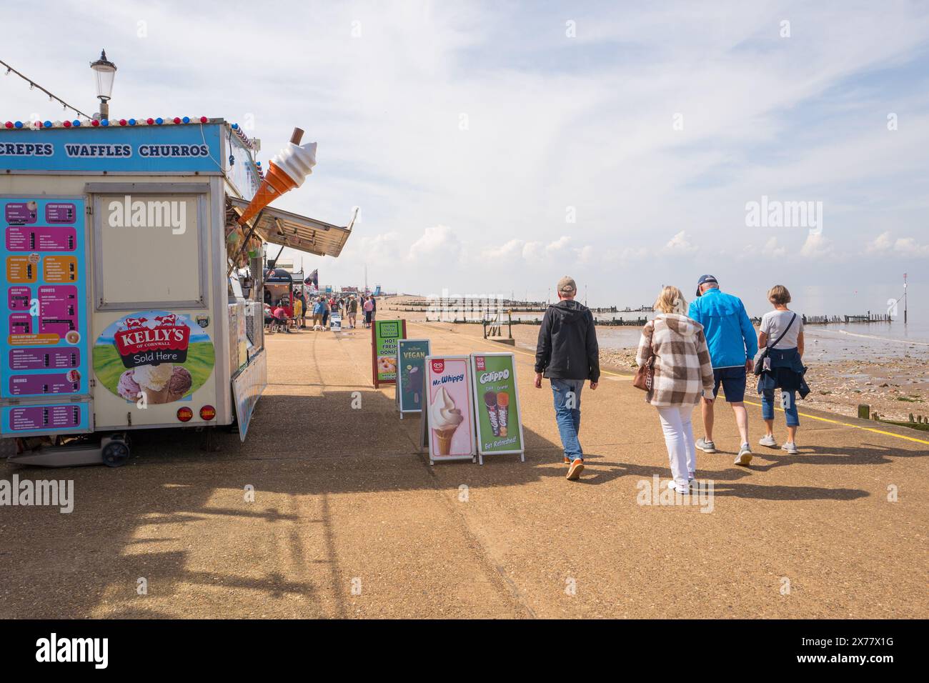 Holiday makers walking the concrete sea wall and promenade at the North ...